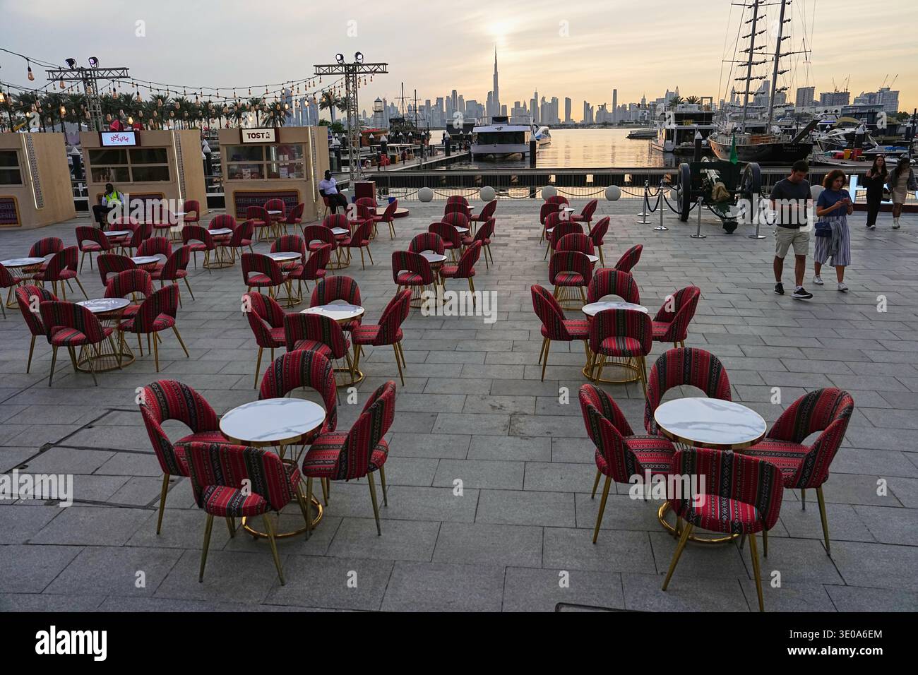 People walk past an outdoor empty restaurant at Dubai Creek Harbour in ...