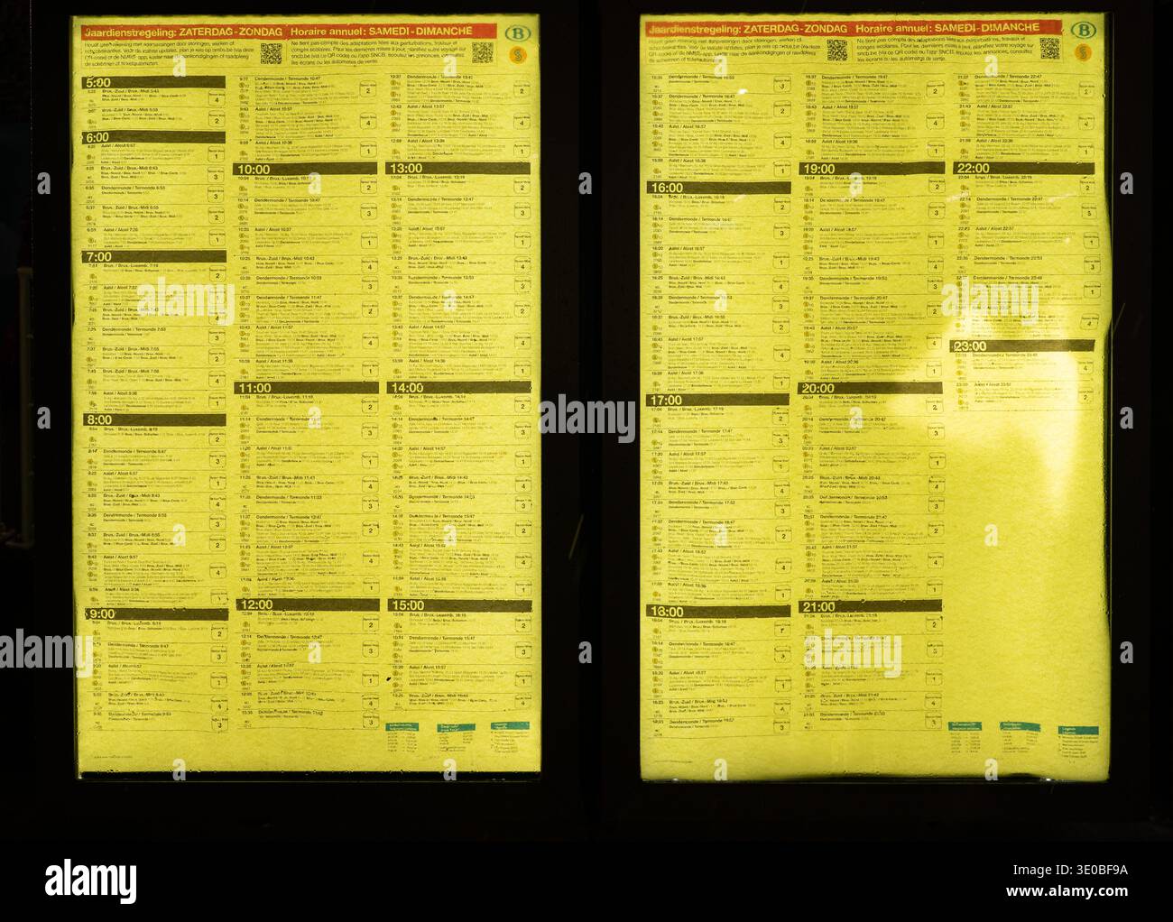 Illuminated yellow paper train timetables displayed at Jette station ...