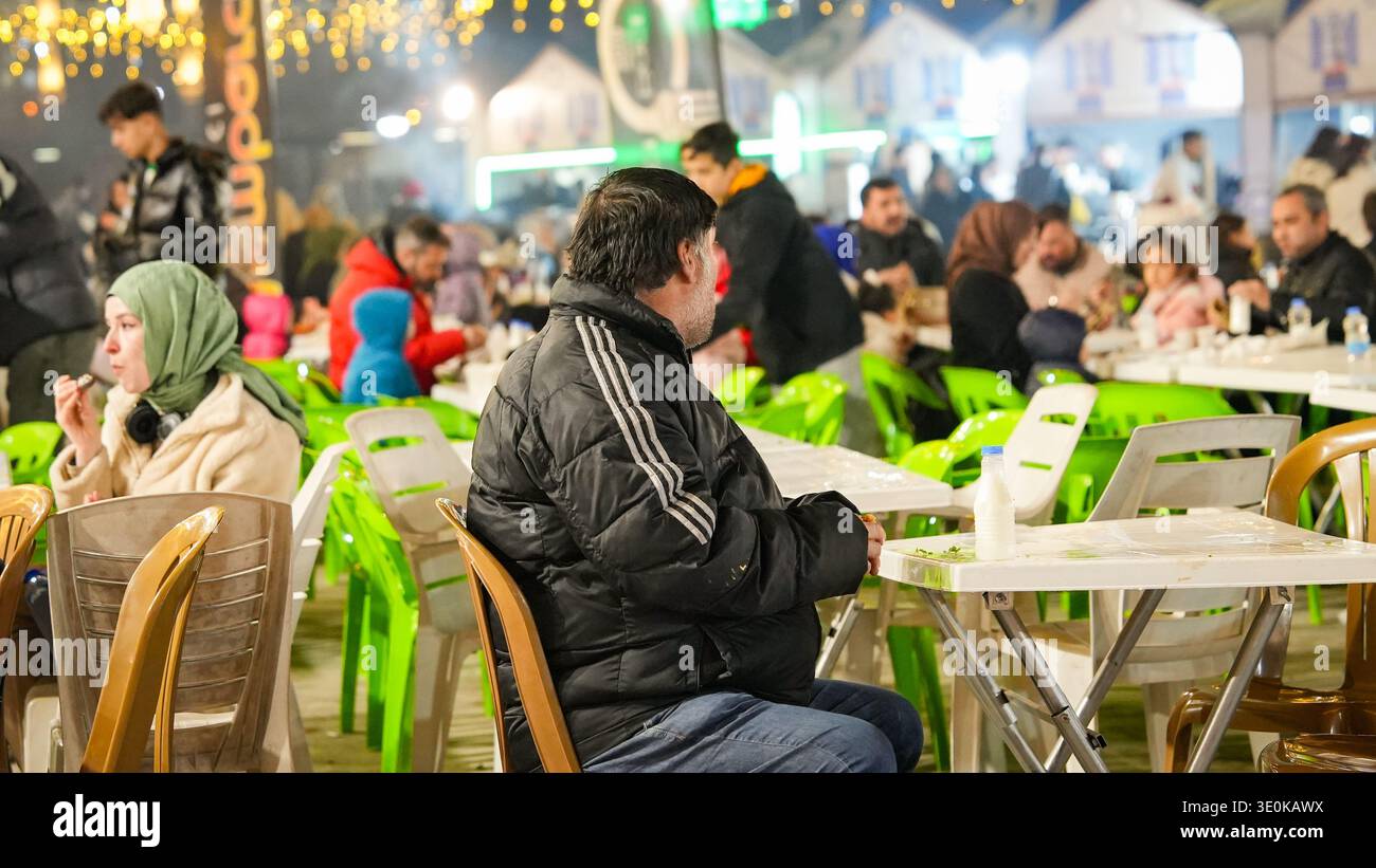 Muslim families and individuals gather at outdoor tables for a mass ...