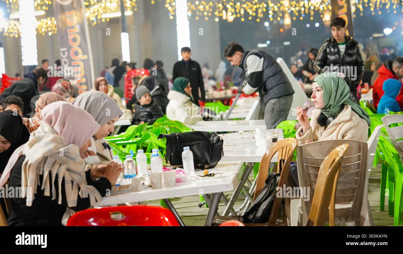 Muslim families and individuals gather at outdoor tables for a mass ...