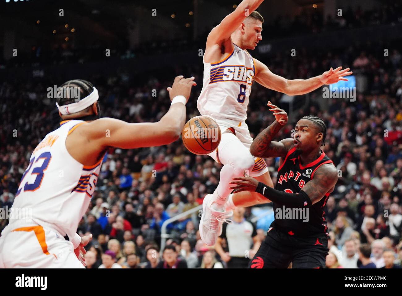 Toronto Raptors' Jamal Shead (right) passes between Phoenix Suns ...