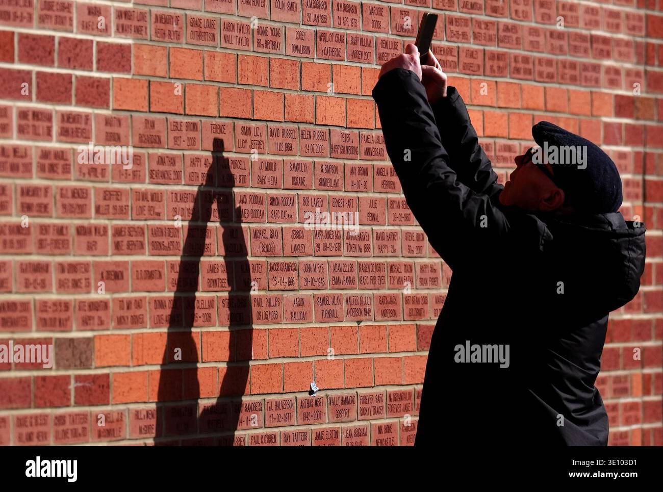 A fan takes a photo of names in bricks of the stadium ahead of the ...