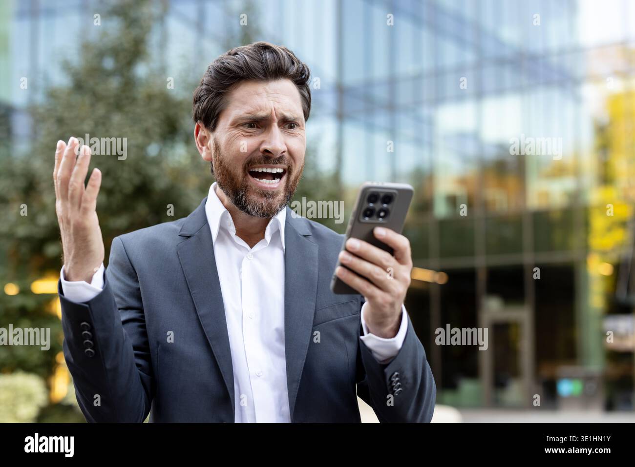 Businessman looking angry and stressed, shouting at his mobile phone ...