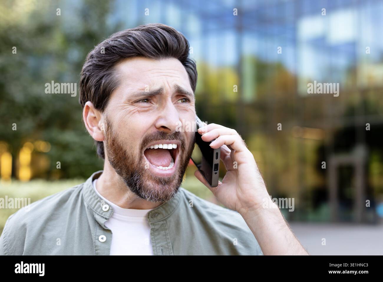 Frustrated man expressing anger and screaming into smartphone during ...