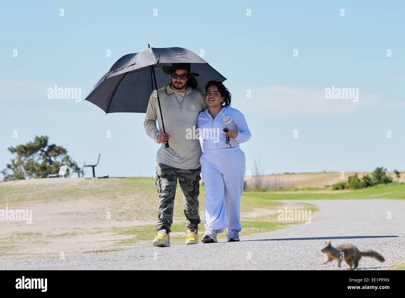 Juan Olmedo, left, and his wife Alejandra Delgado use an umbrella to ...