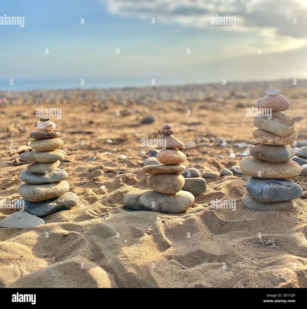 Balanced stacked stones on sandy beach with soft ocean background and ...