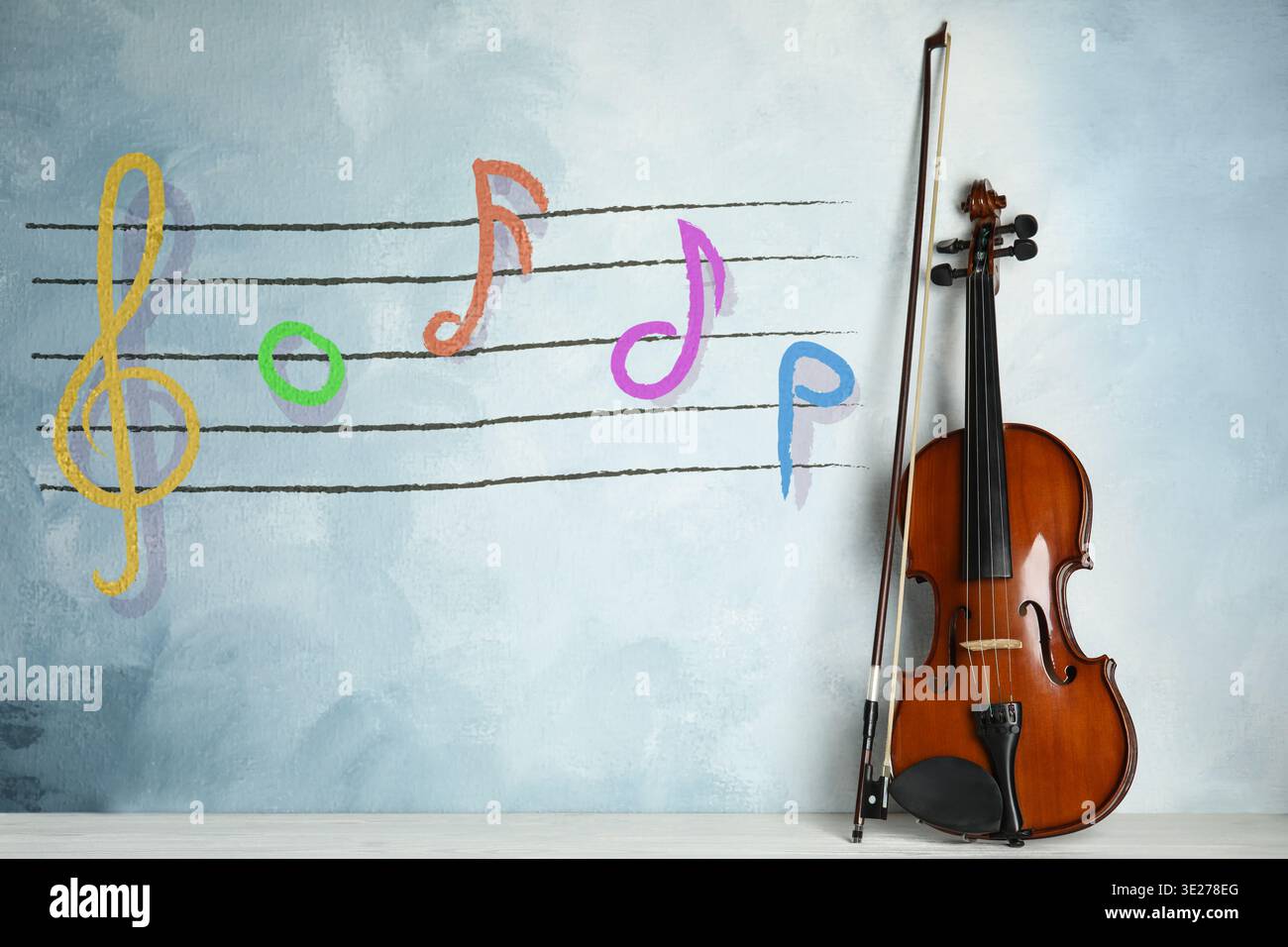 Violin and bow near wall with drawing of musical staff with treble clef ...