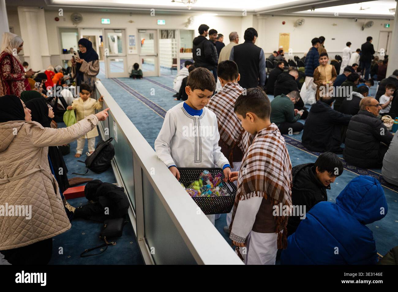 A young boy hands out snacks at Eid al-Fitr at an ISNA Canada mosque in ...