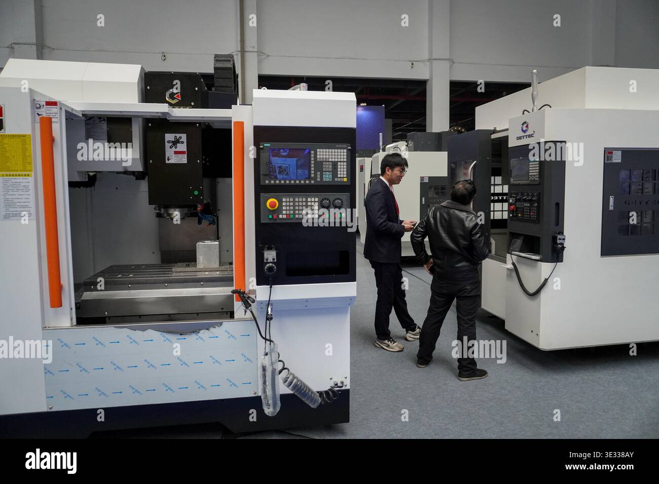 A salesman explains a CNC machining center to a visitor at the ...