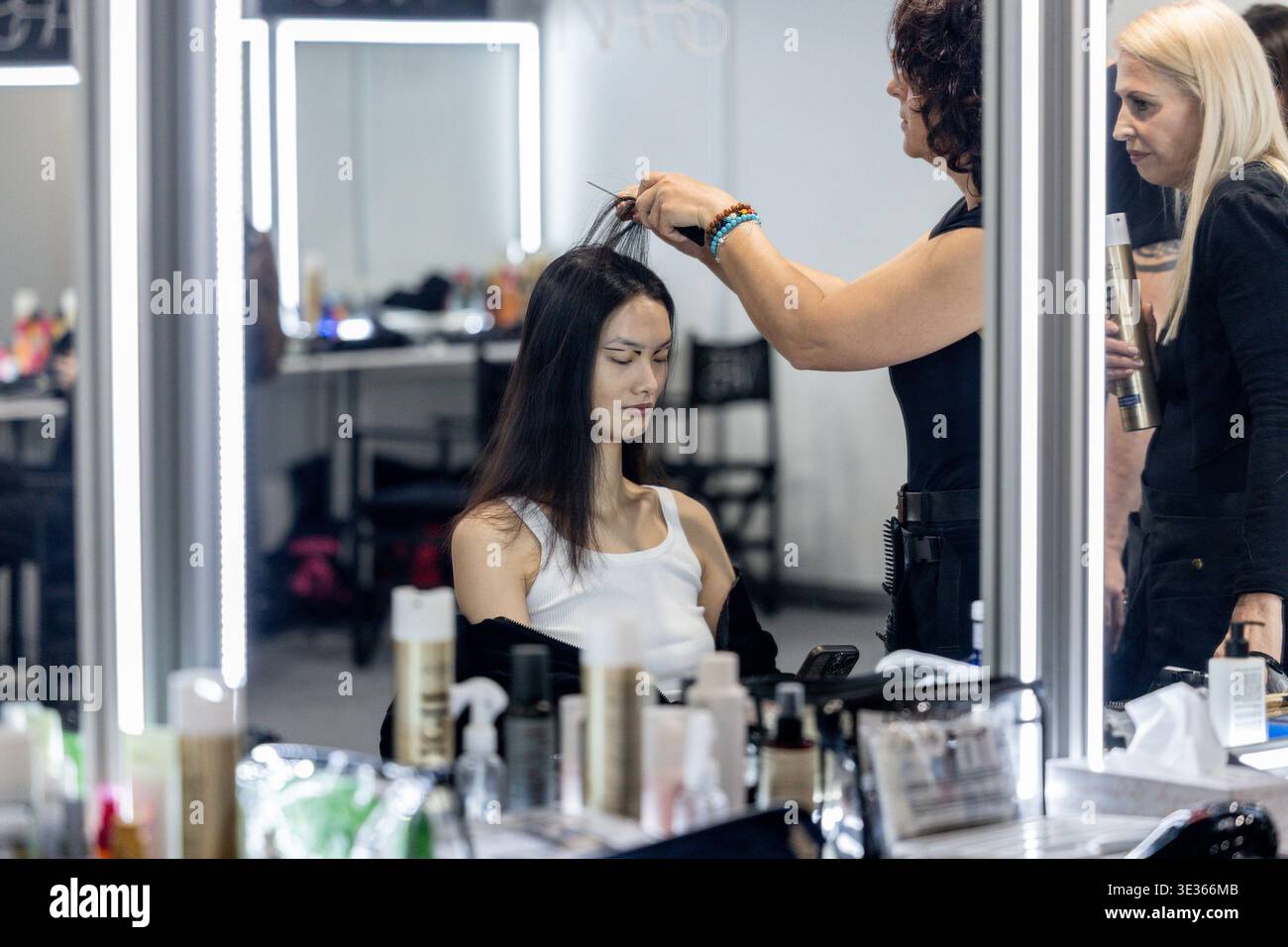 A hairdresser styles a model backstage during Madrid Fashion Week 2026 ...