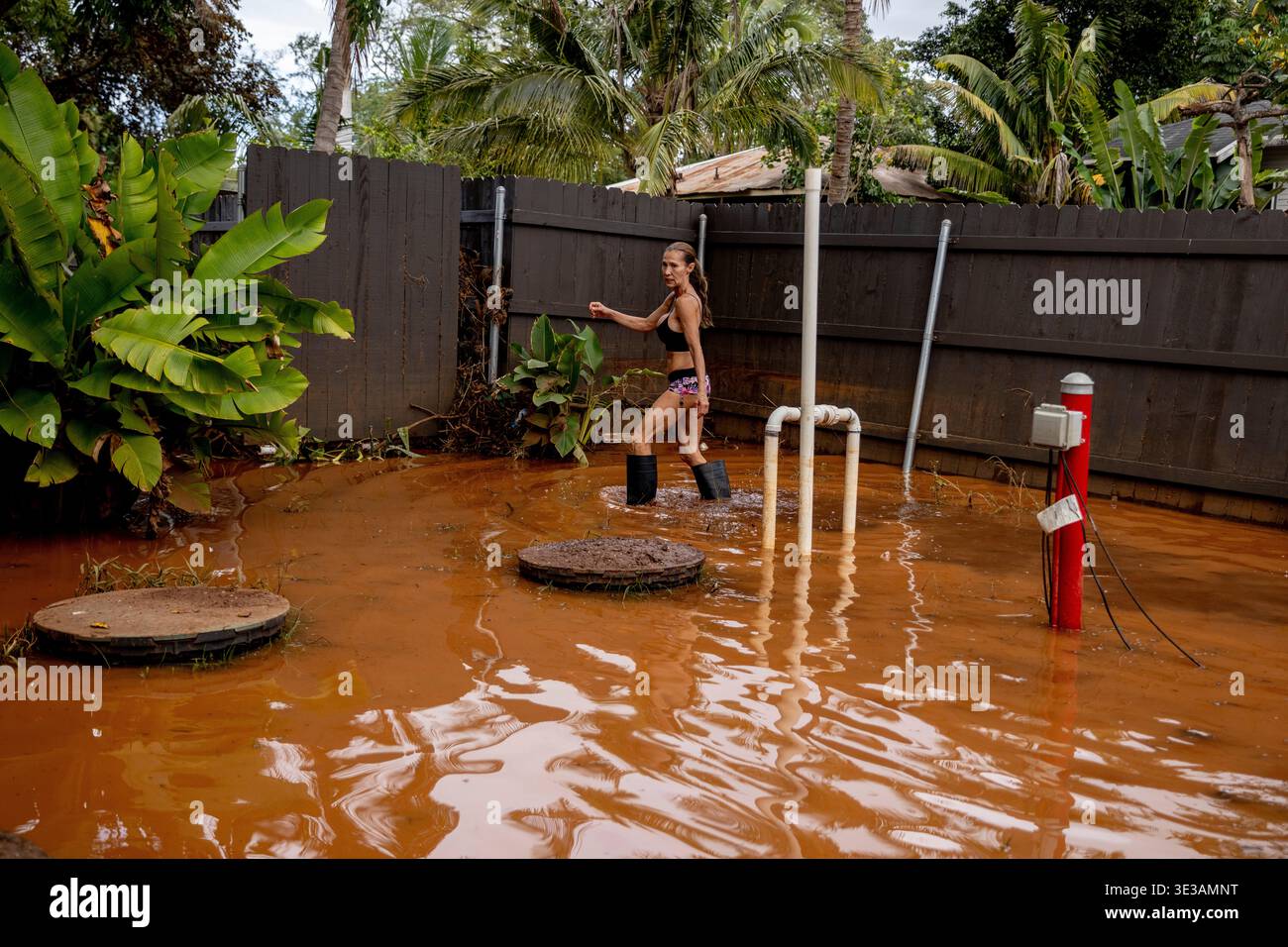 Linda Griffith wades through a flooded yard in Haleiwa, Hawaii Saturday ...