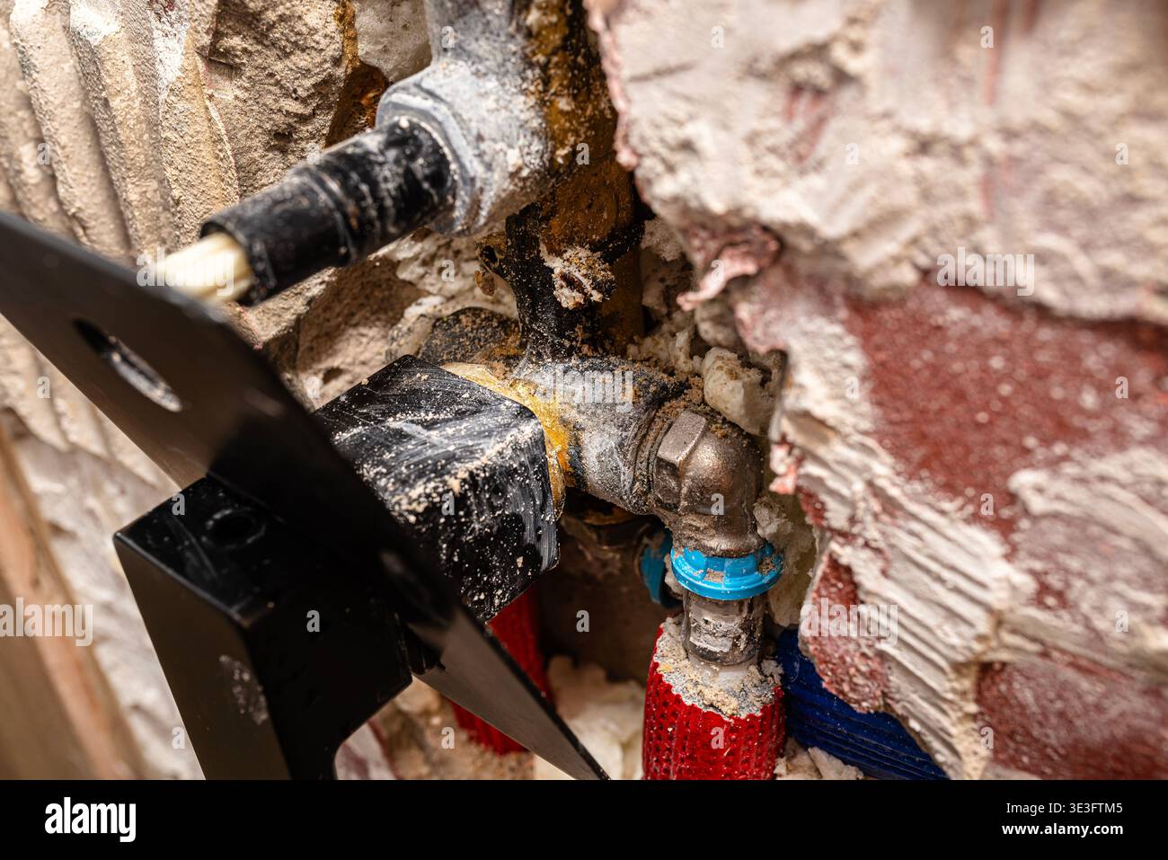 Water leaking from a damaged plumbing valve and pipes in a brick wall ...