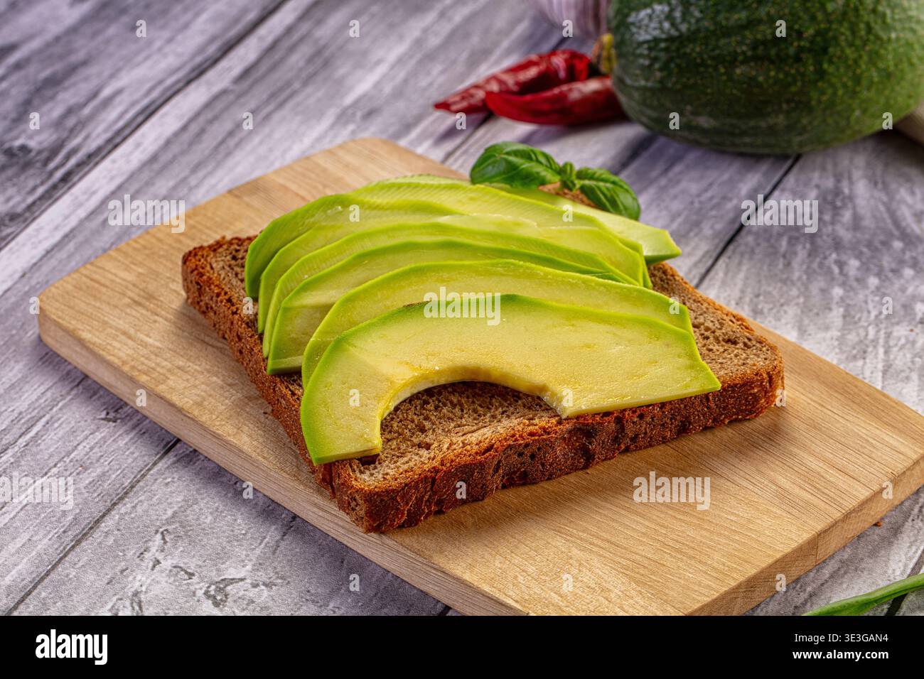 Healthy avocado toast on dark rye bread, served on a wooden board ...