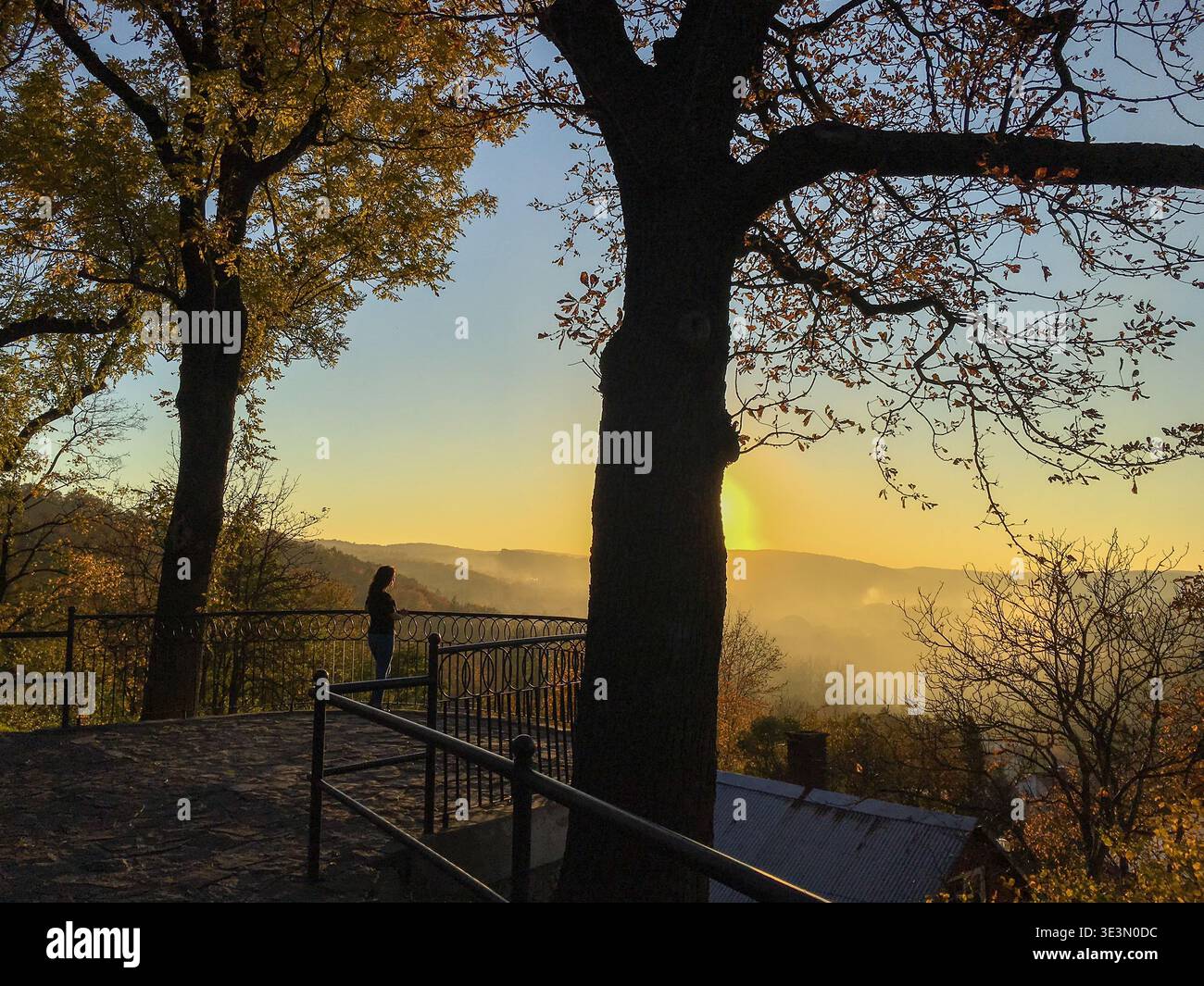 A person stands on a viewpoint looking out over the mountains and ...