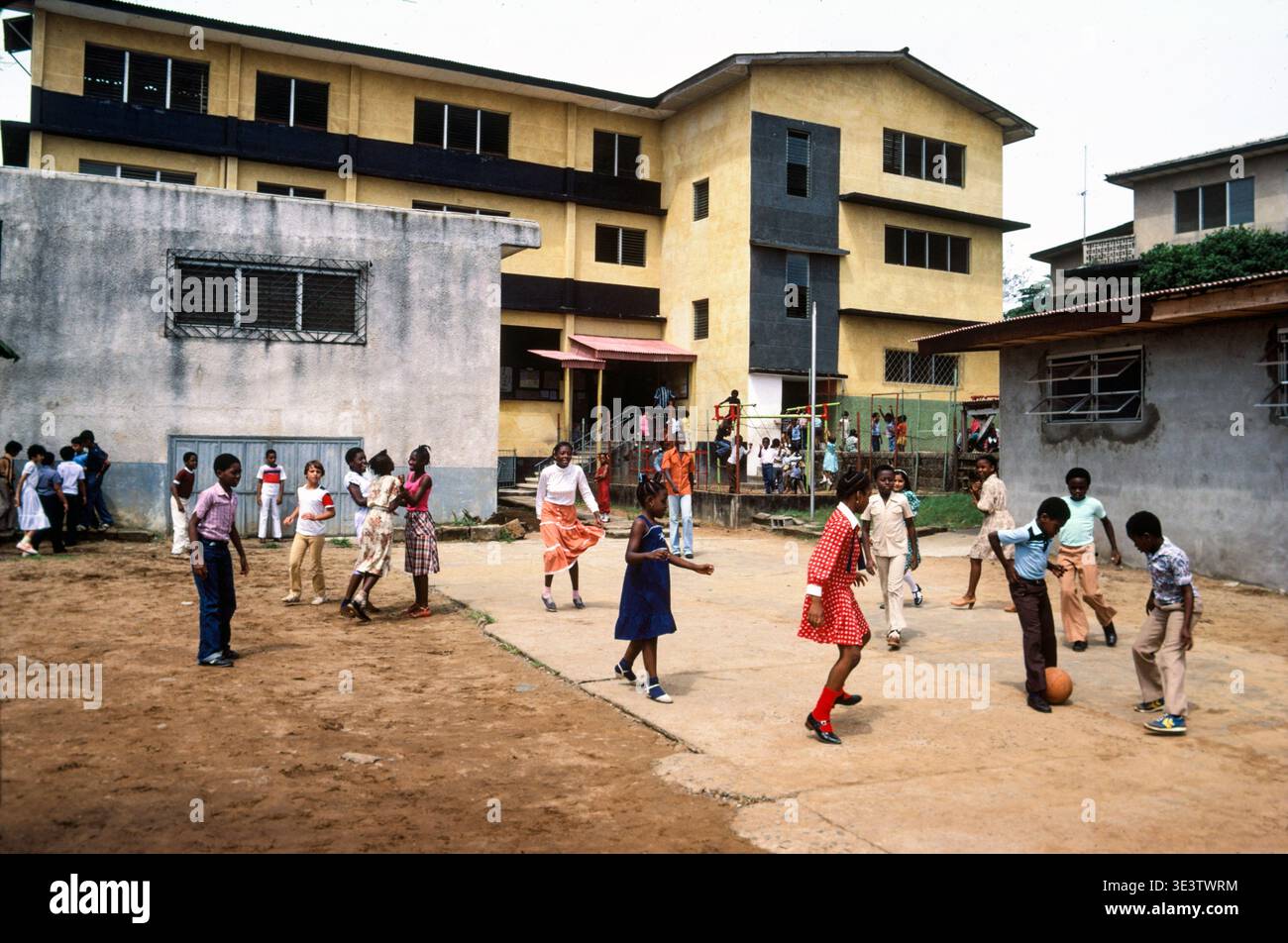 School children playing football in the playground. School building ...