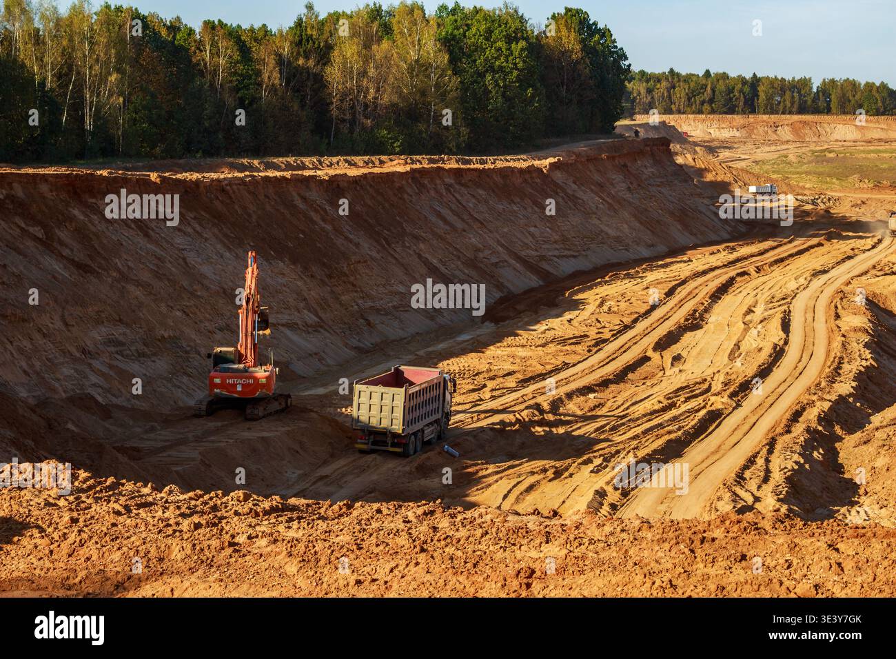 Massive excavator and dump truck at work in a sprawling open-pit sand ...
