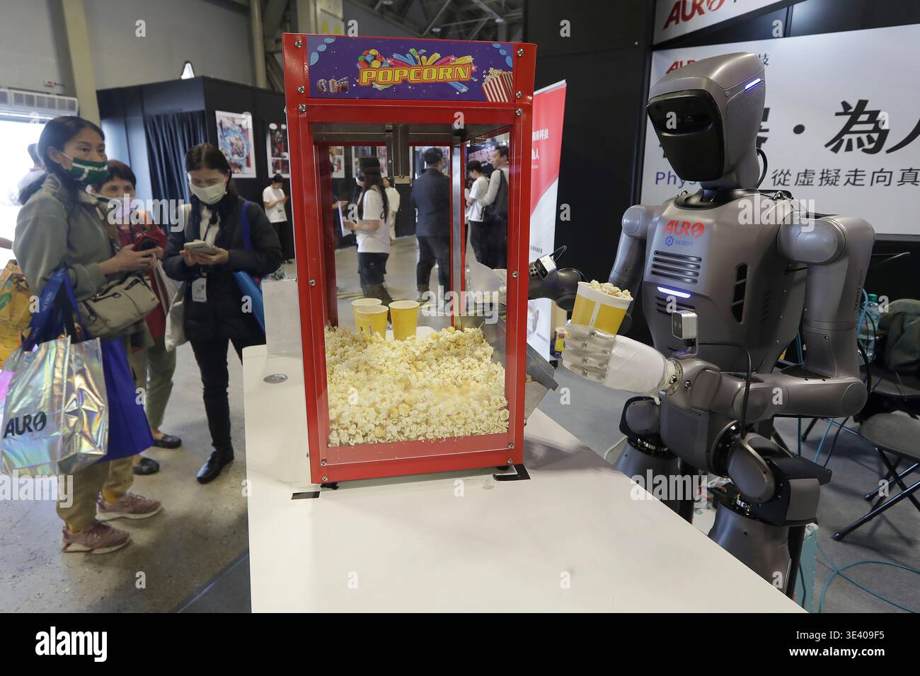 People watch a Dobot Atom Max of AURO serve popcorn during the AI EXPO ...