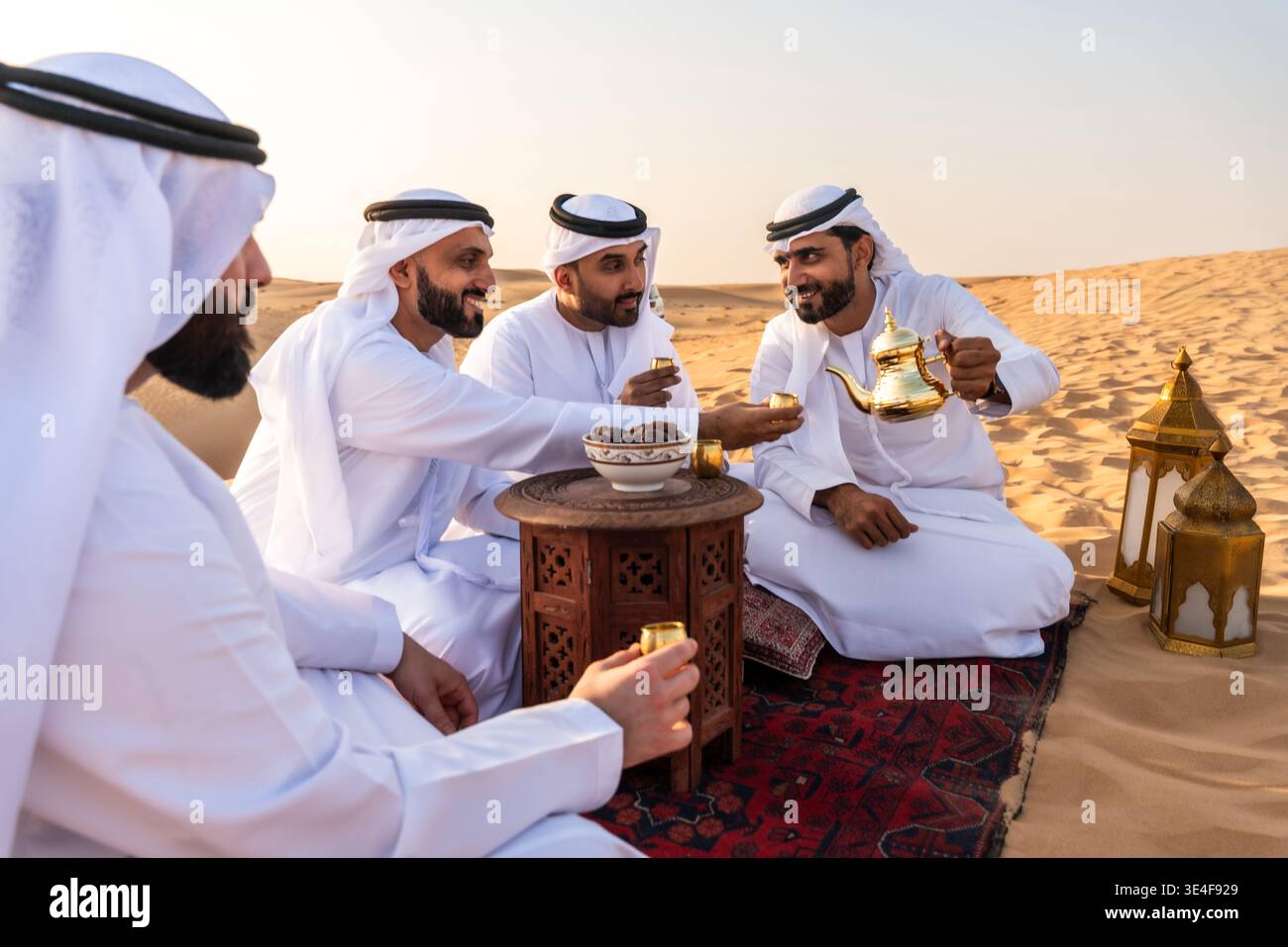 Middle eastern men wearing traditional emirati kandura sharing coffee ...