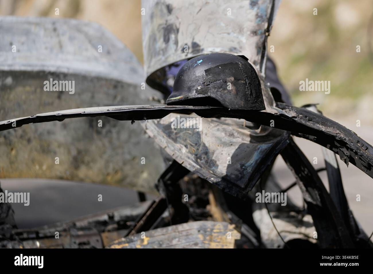 A burned press helmet rests on the charred car that was carrying ...