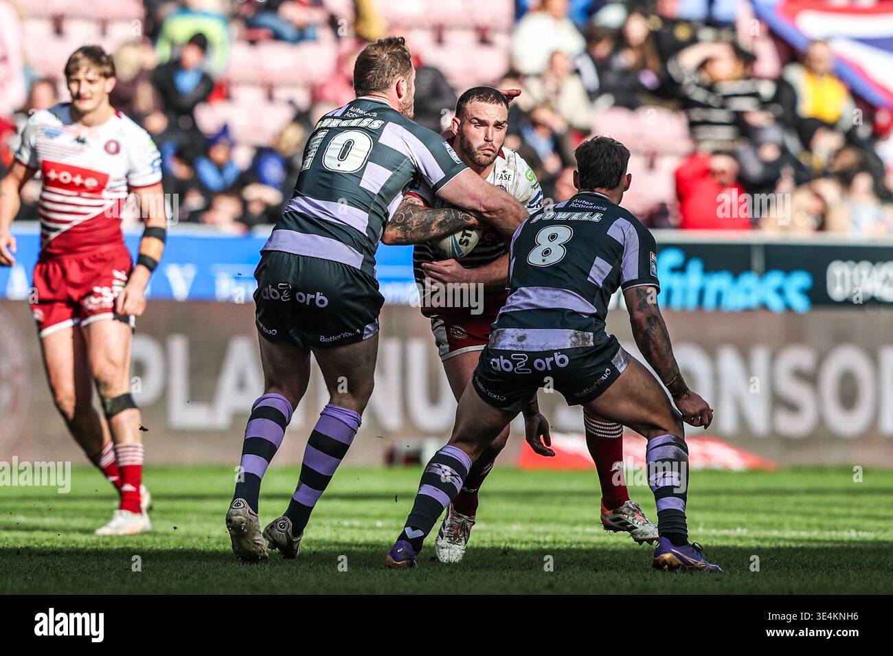 Kaide Ellis of Wigan Warriors is tackled by Tom Burgess of Huddersfield ...