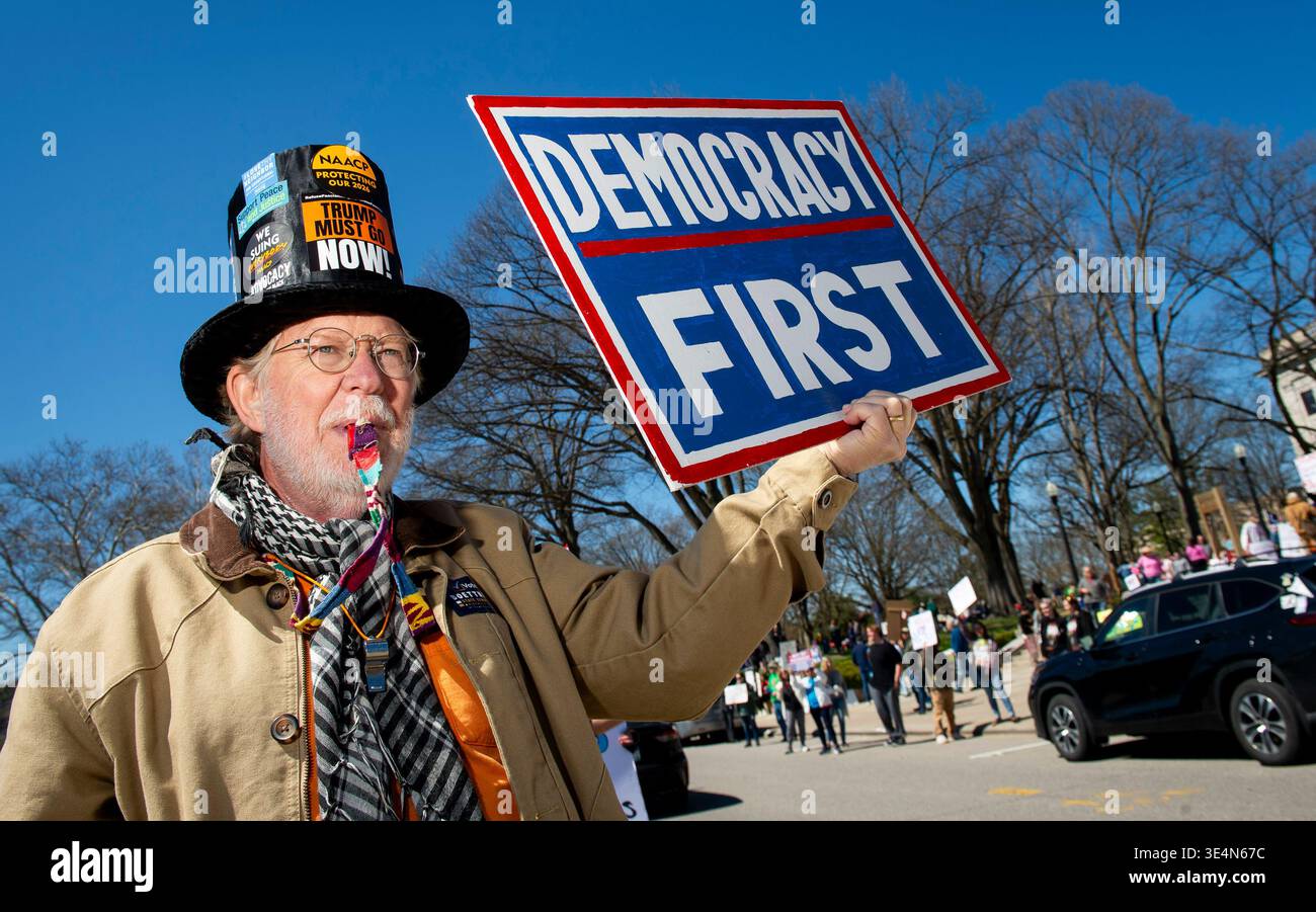 John Doyle blows a whistle and holds a sign at a 'No Kings' protest ...