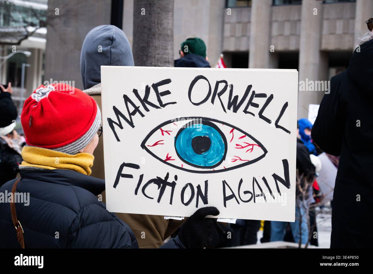 A protest sign reads “Make Orwell Fiction Again” referring to George ...