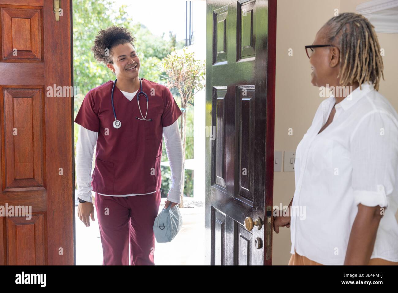 Mid adult male caregiver in scrubs holding stethoscope and cap with ...