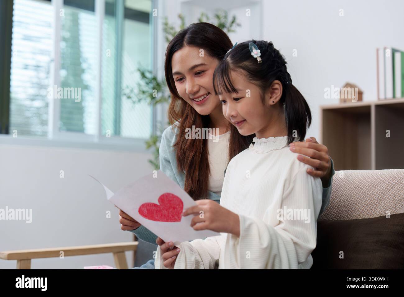 Mother and daughter sharing a heartfelt moment with a card Stock Photo ...