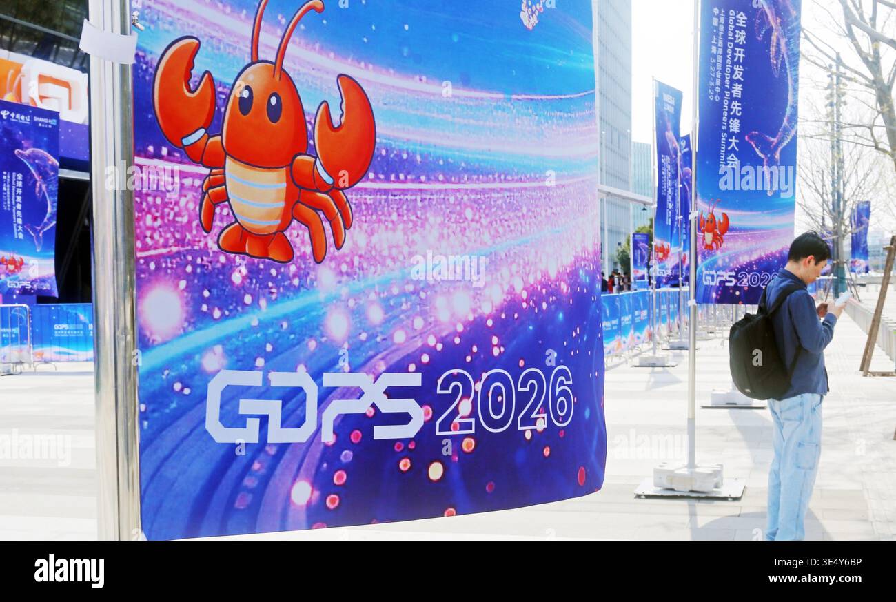 A man stands by posters promoting OpenClaw-based AI agents during a ...
