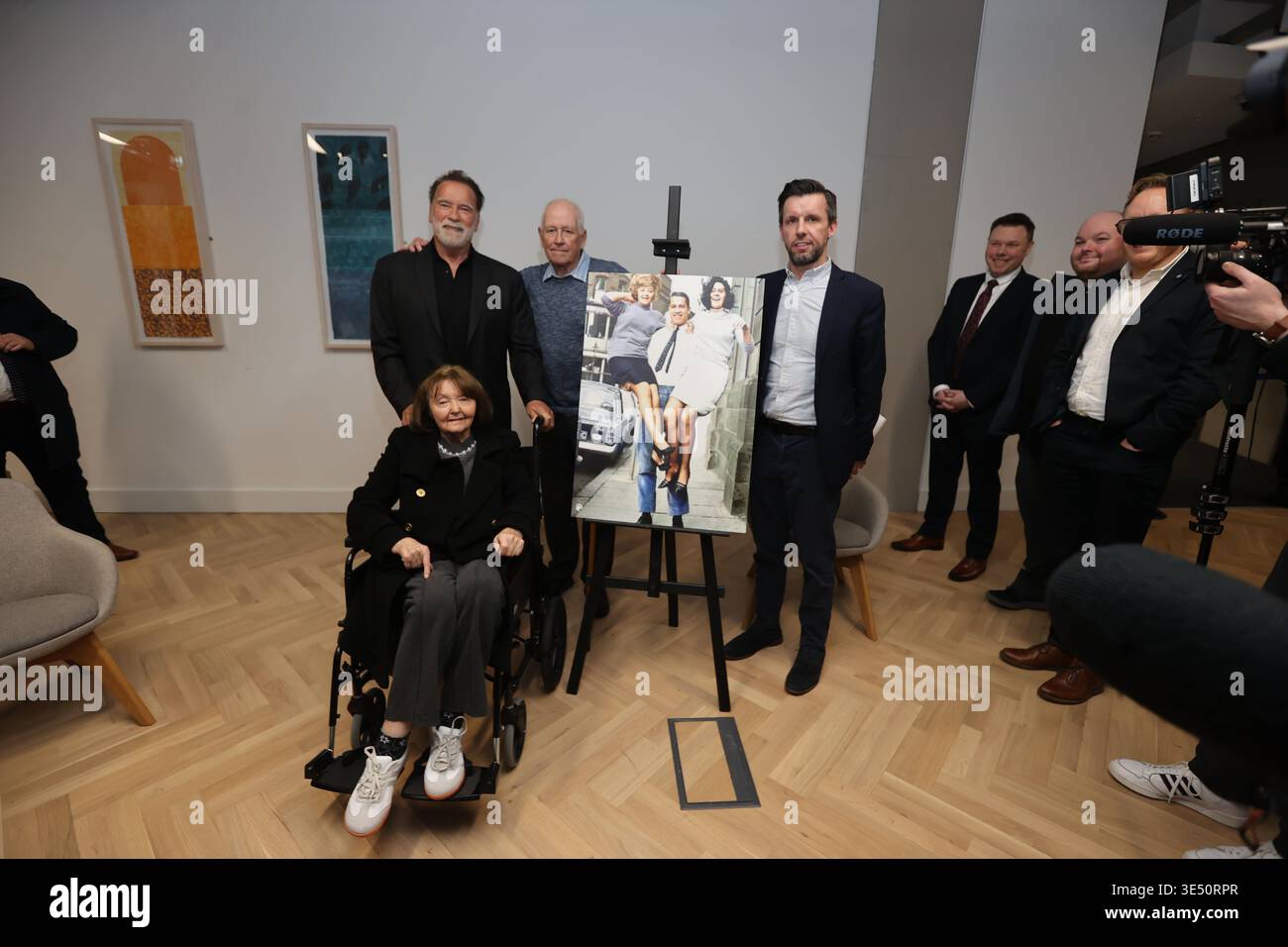 Arnold Schwarzenegger (left) poses for a picture next to a picture of ...