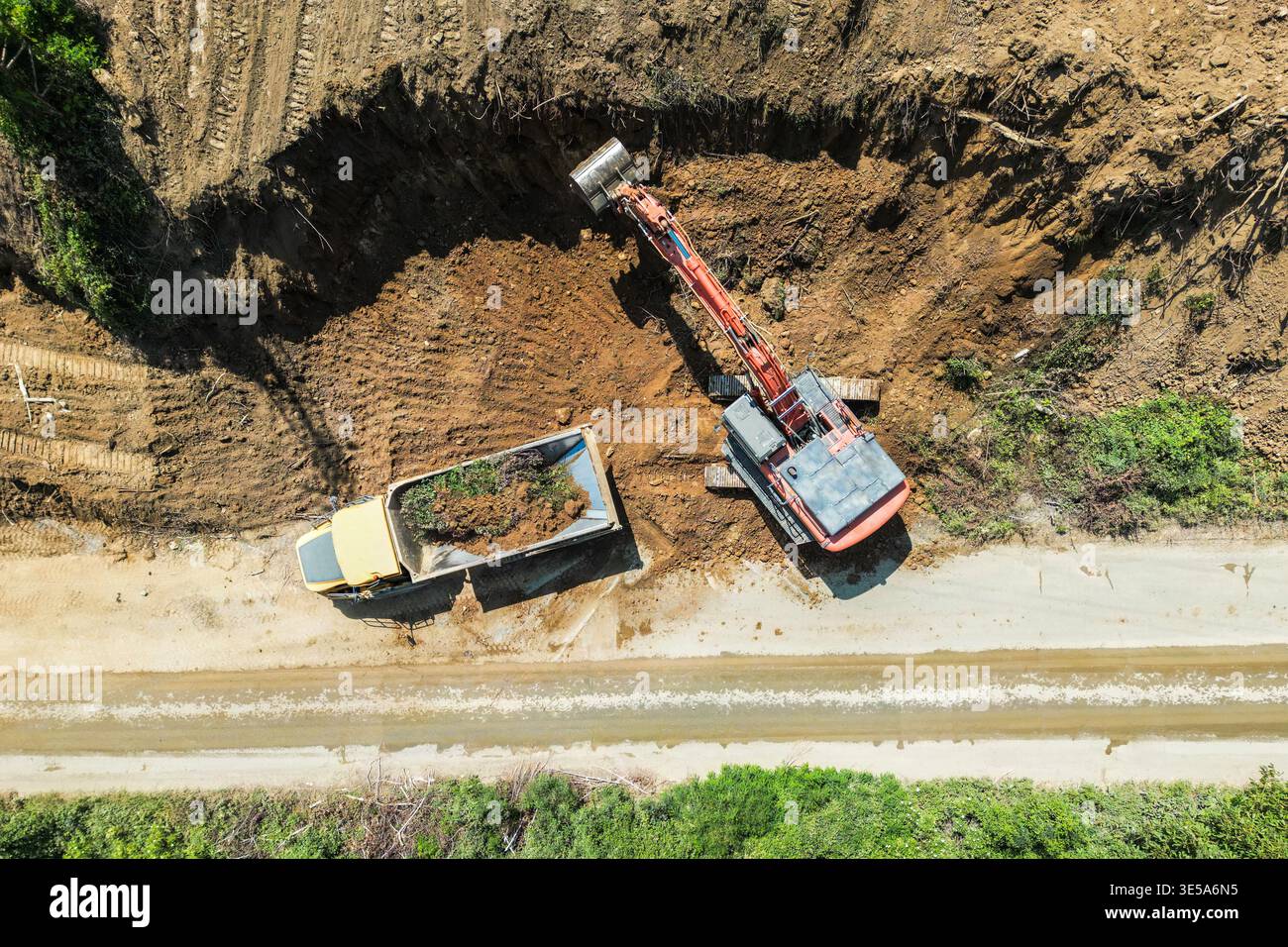 Excavator loading a truck on construction site of a new road, aerial ...