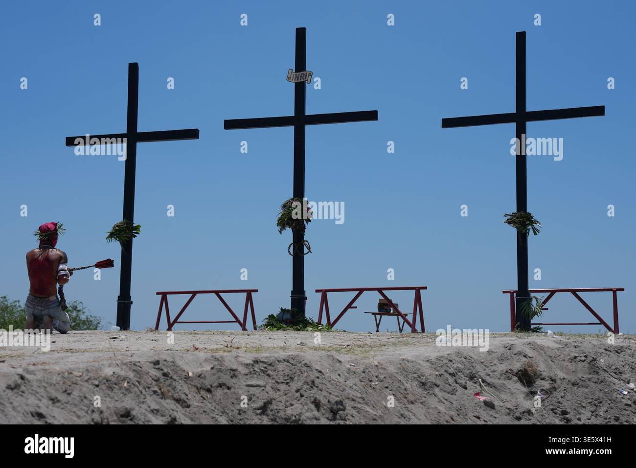 A flagellant prays in front of the cross during Good Friday rituals in ...