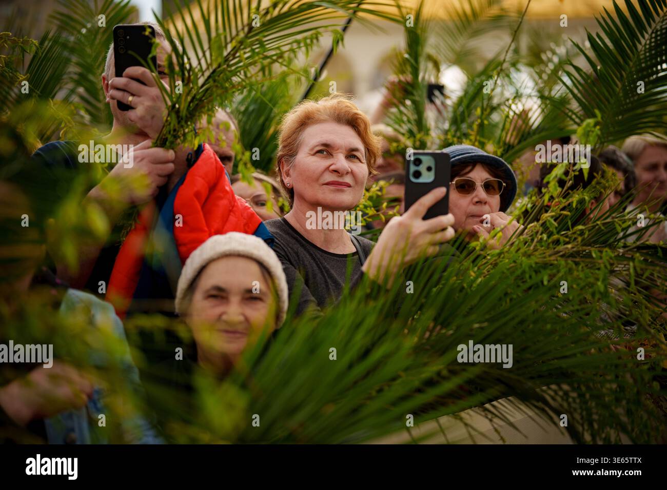 People holding palm fronds watch Romanian Orthodox priests during an ...