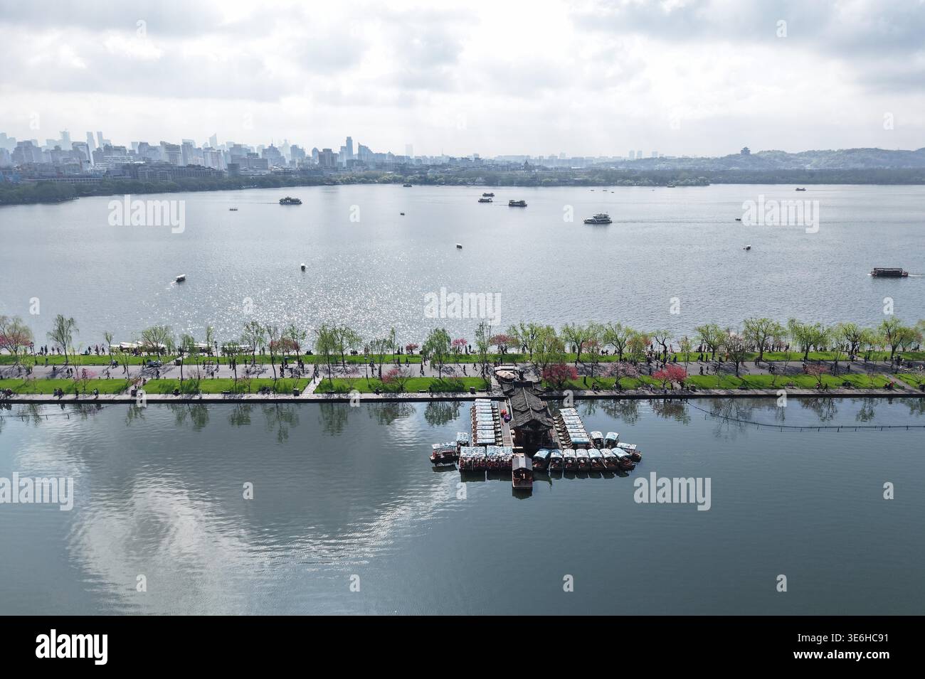 Tourists enjoy the spring scenery of peach blossoms and willow greens ...