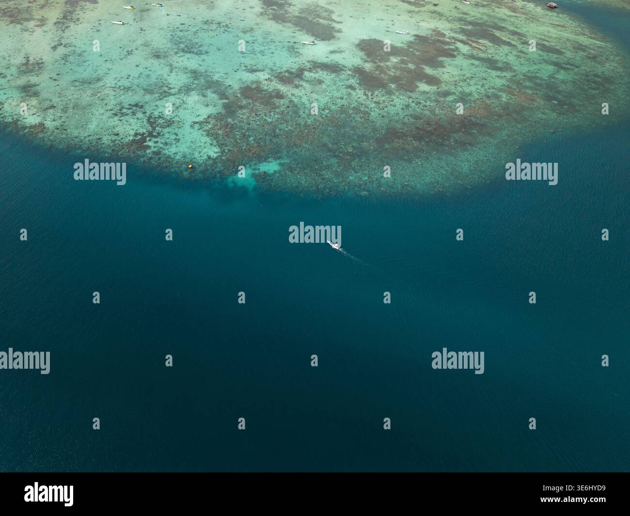 Aerial view of a solitary boat glides across the tranquil, deep blue ...