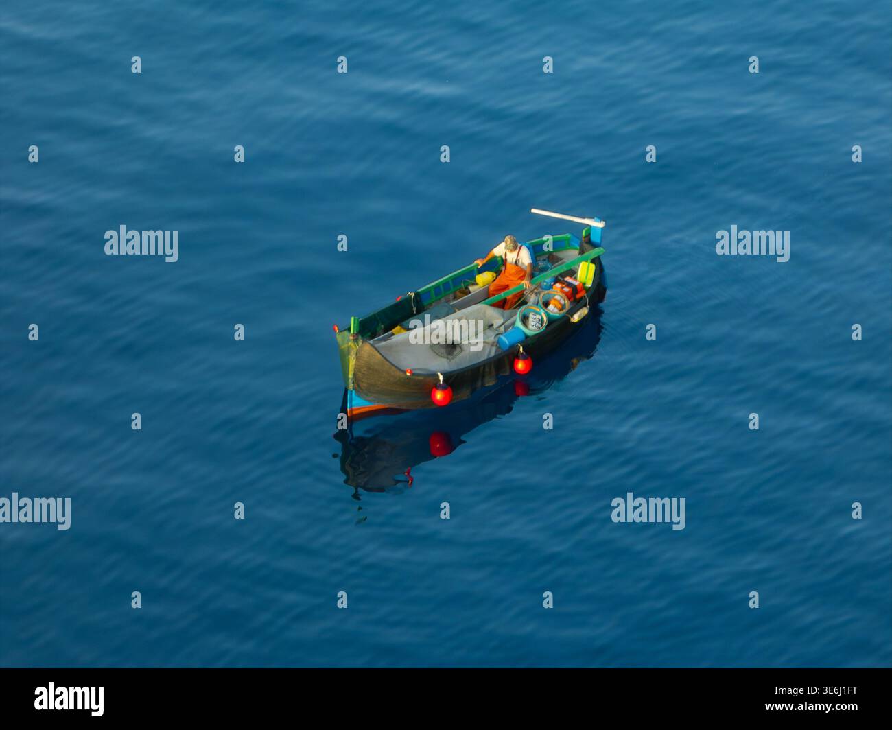 Aerial view of a small boat adrift on the tranquil, sapphire expanse of ...