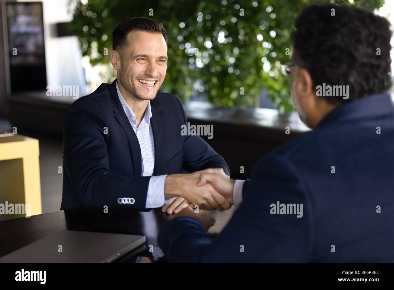 Two businessmen or applicant and HR manager handshaking sitting at ...