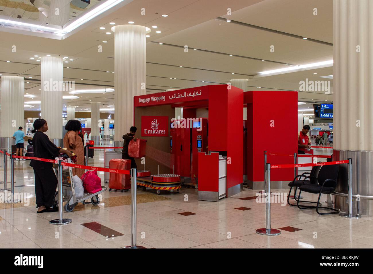 Passengers waiting at an Emirates baggage wrapping station inside Dubai ...
