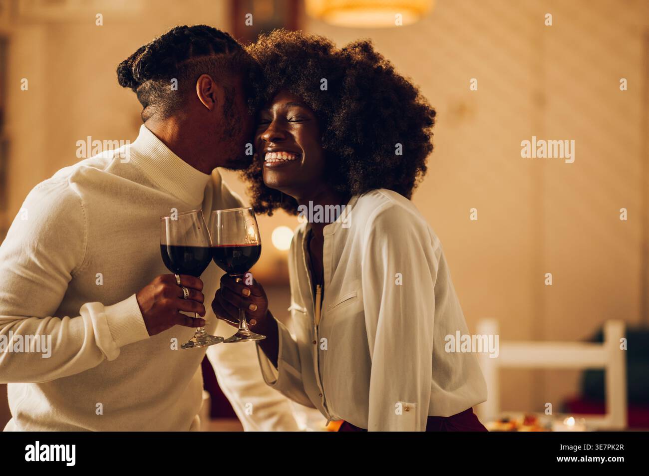 Cheerful Black couple standing together clinking wine glasses and ...