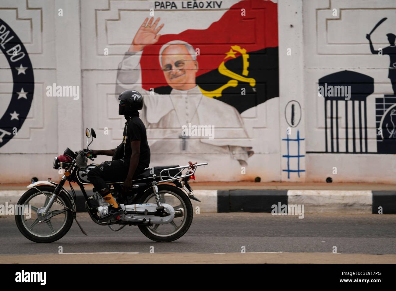 A man riding motorcycle past a mural of Pope Leo XIV in Luanda, South ...