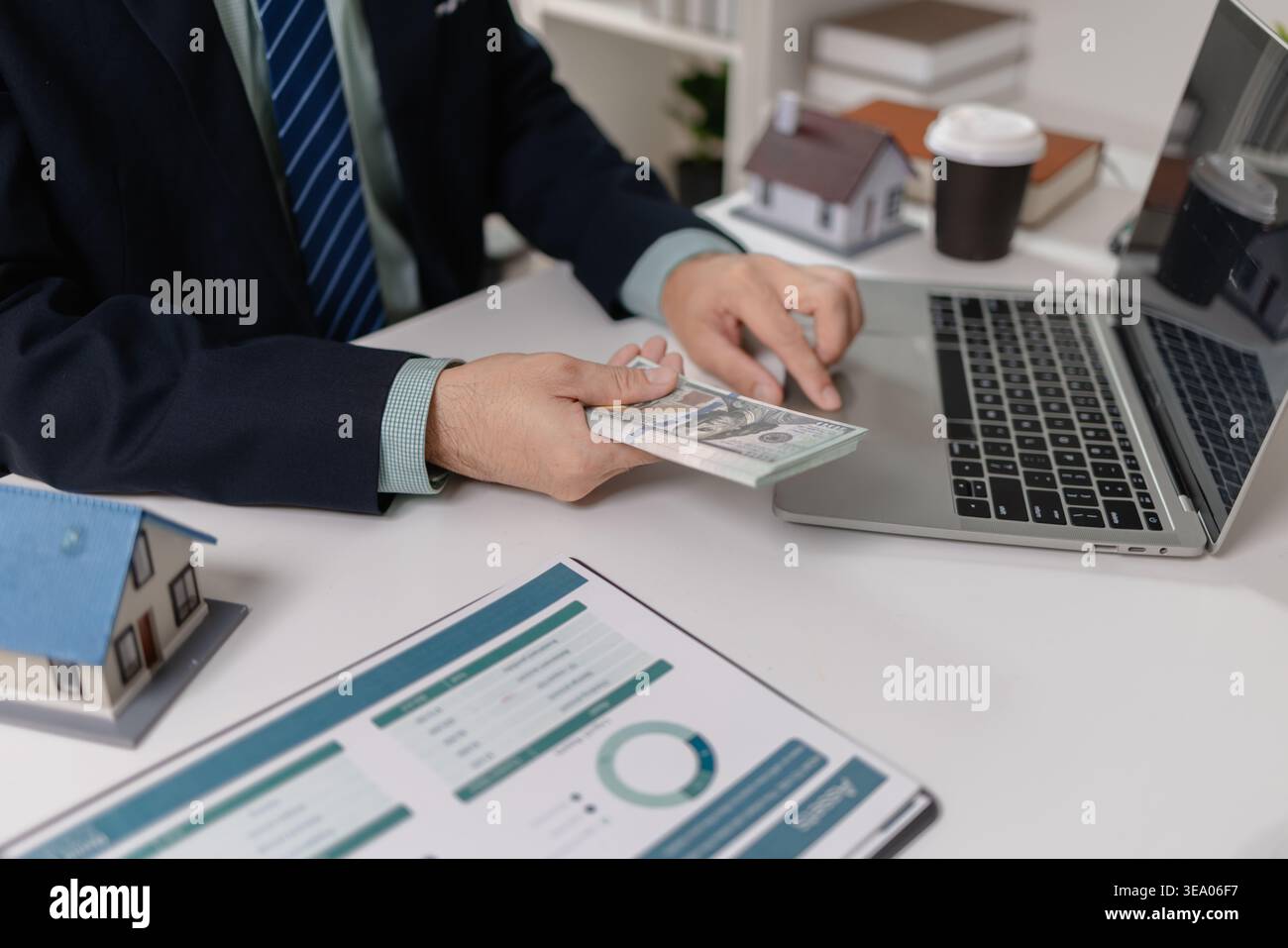 Businessman counting cash with property model and financial report on ...