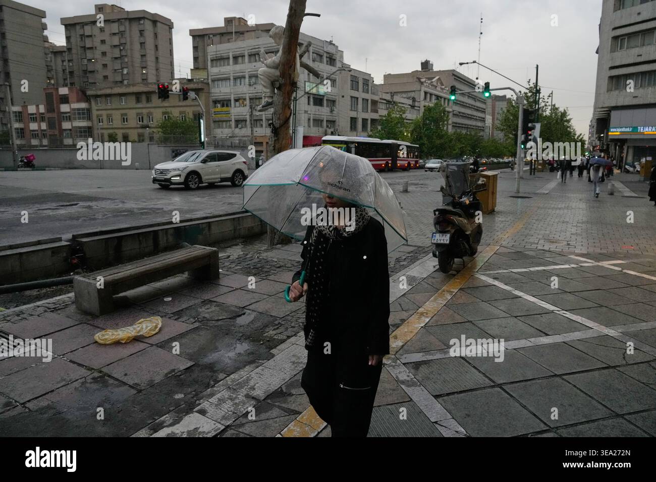 A woman uses umbrella as she walks on a sidewalk in downtown Tehran ...