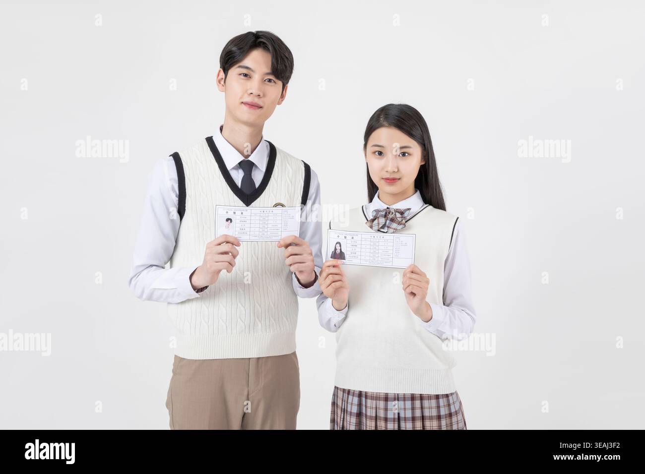 Two Asian high school students holding their student ID cards in front ...