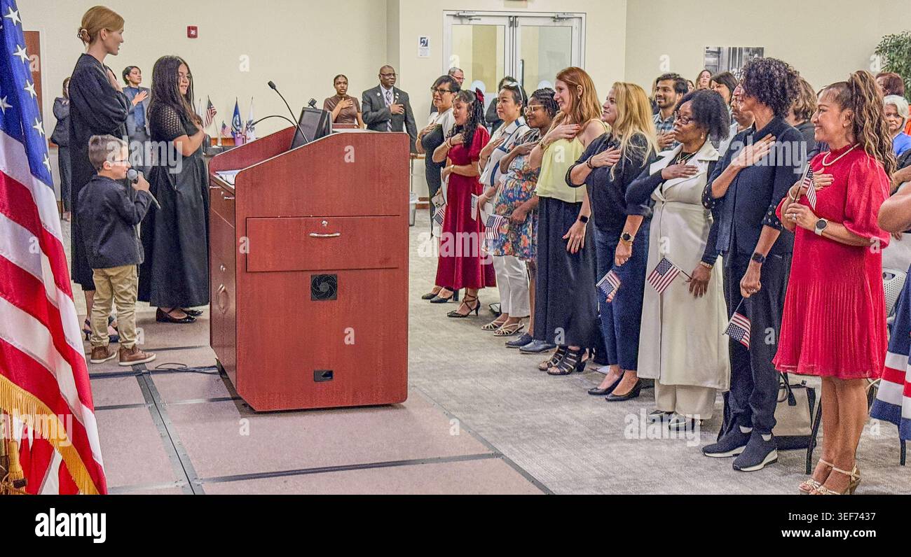 A group of new U.S. citizens, at right, observe the Pledge of ...