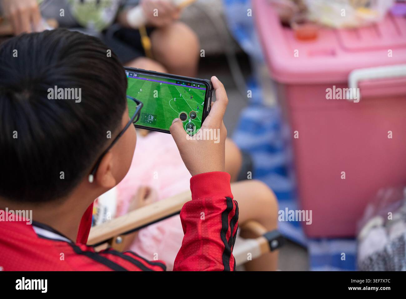 PHAYAO, THAILAND-APR 11, 2026: Boy sitting playing game on smartphone ...