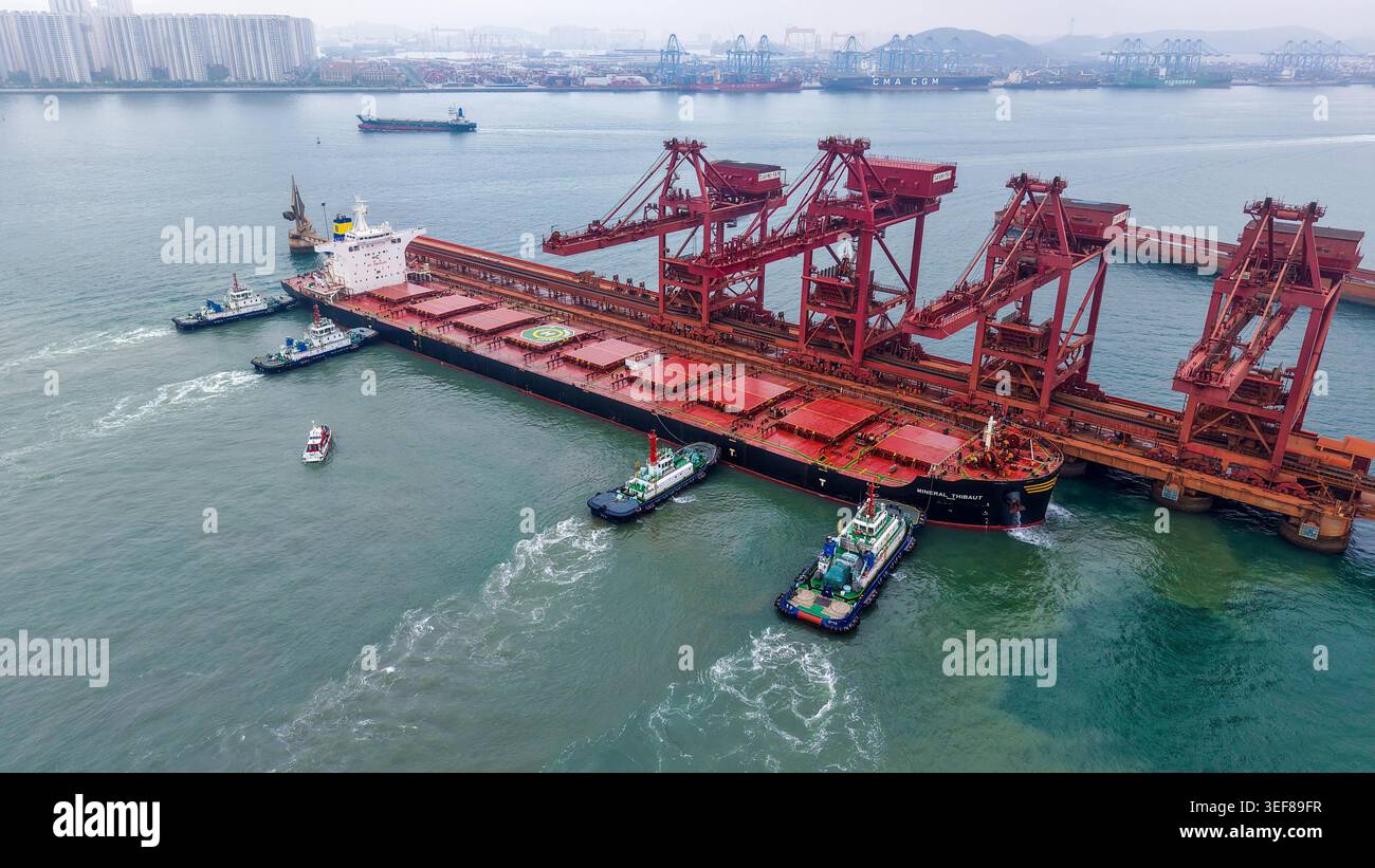 Workers handle cargo at the iron ore terminal of Qingdao Port in east ...