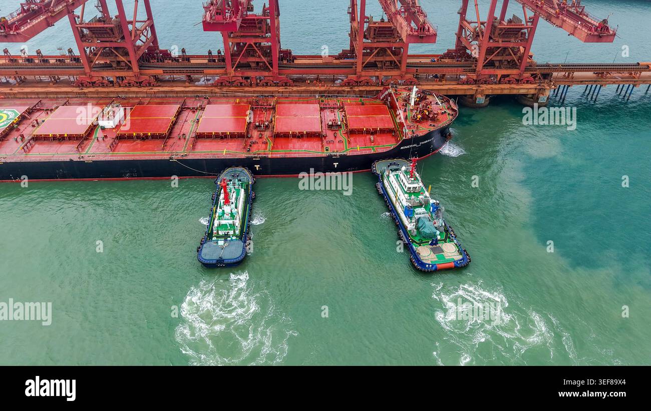 Workers handle cargo at the iron ore terminal of Qingdao Port in east ...