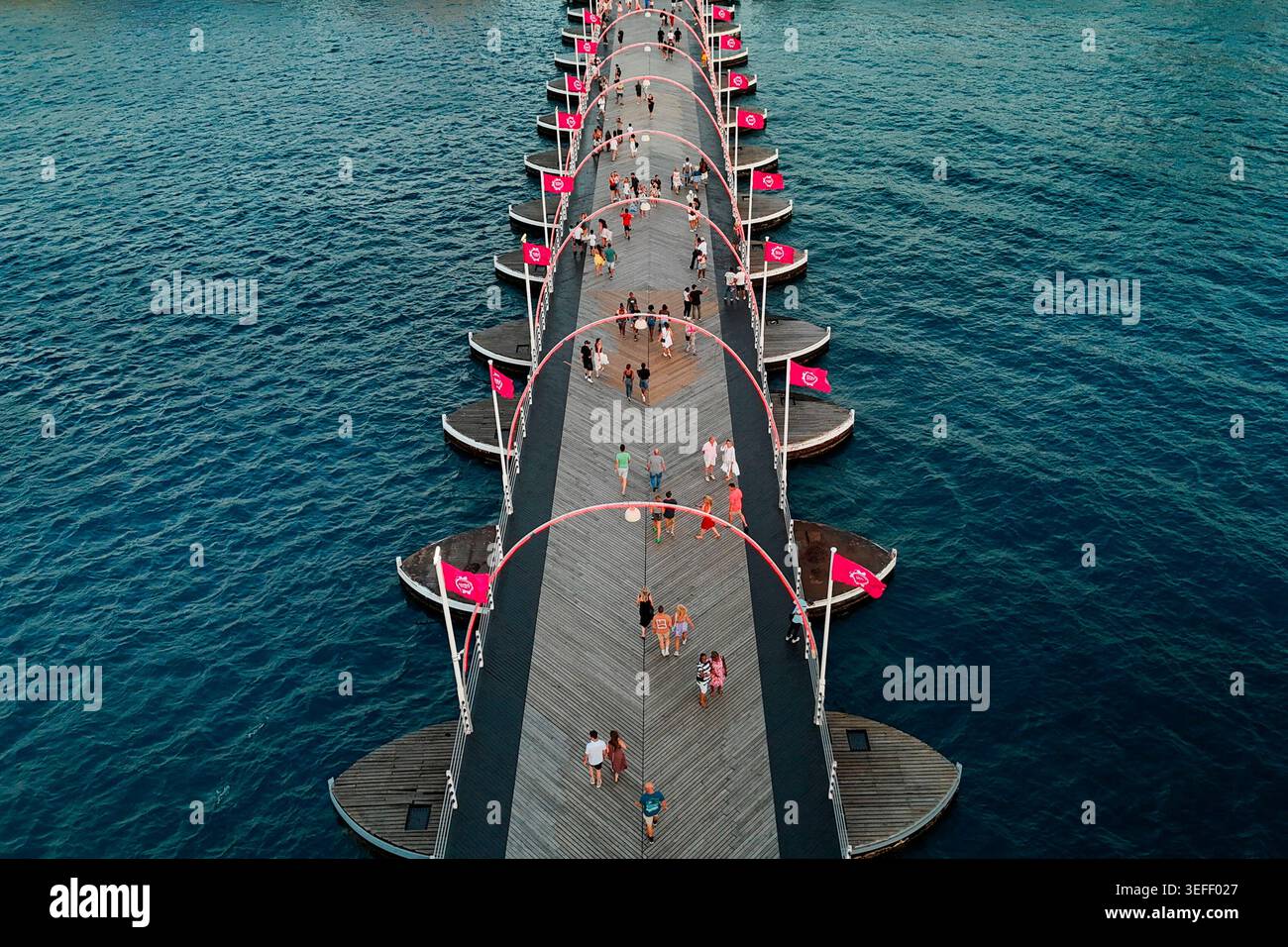 People walk across the Queen Emma Floating Bridge in Willemstad ...