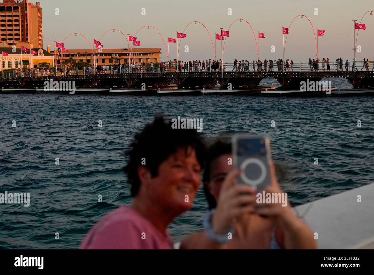 People walk across the Queen Emma Floating Bridge in Willemstad ...