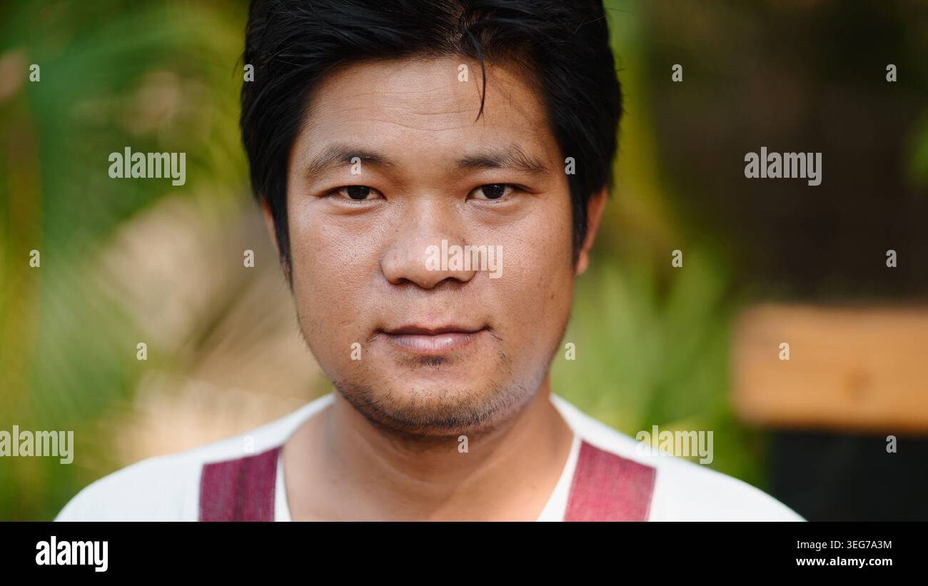 Young asian man looking directly at camera with neutral expression ...